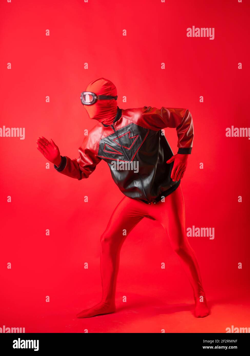 Funny super hero in a red leotard and protective glasses rushes to the ...