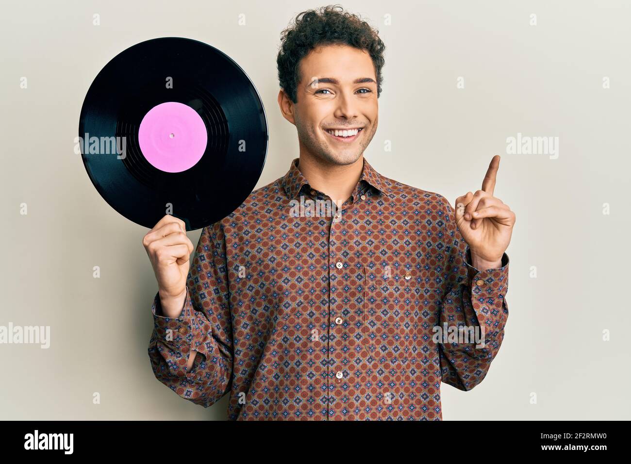 Young handsome man holding vinyl disc surprised with an idea or ...