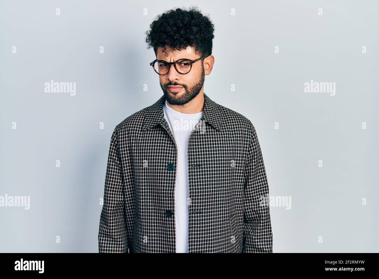 Young arab man with beard wearing glasses skeptic and nervous, frowning ...