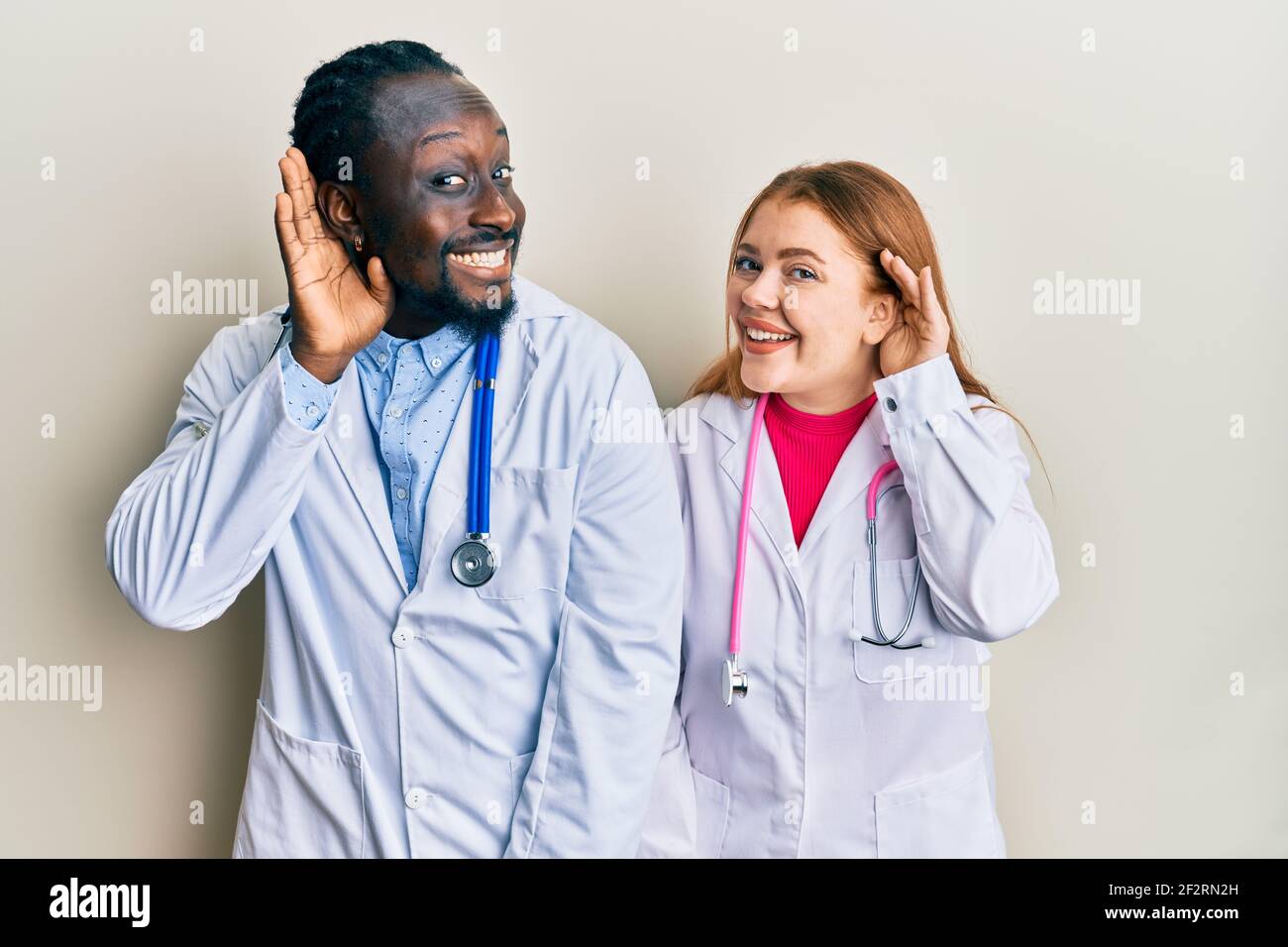 Young interracial couple wearing doctor uniform and stethoscope smiling ...