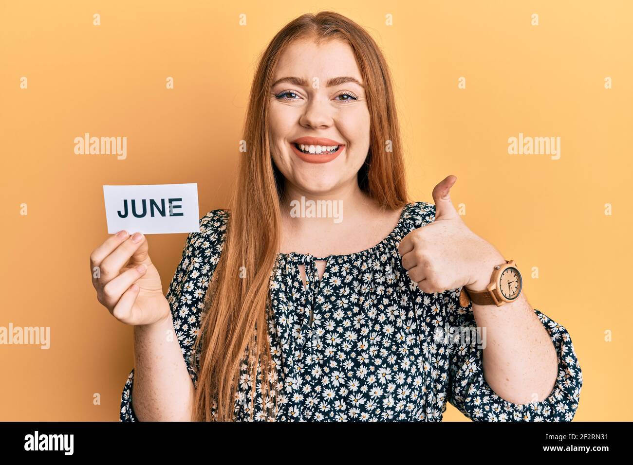 Young beautiful redhead woman holding june word on paper smiling happy ...