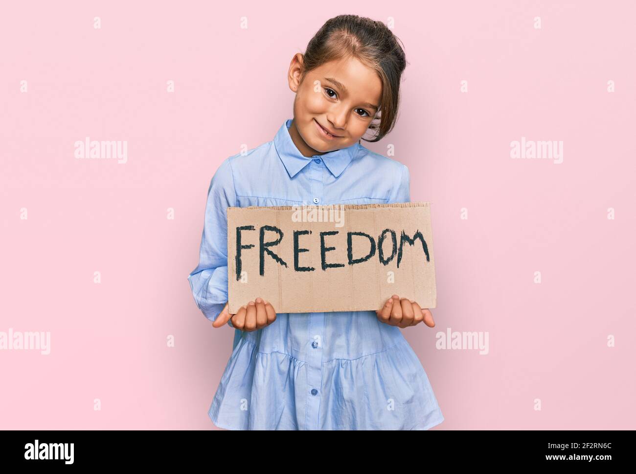 Little beautiful girl holding freedom banner looking positive and happy ...