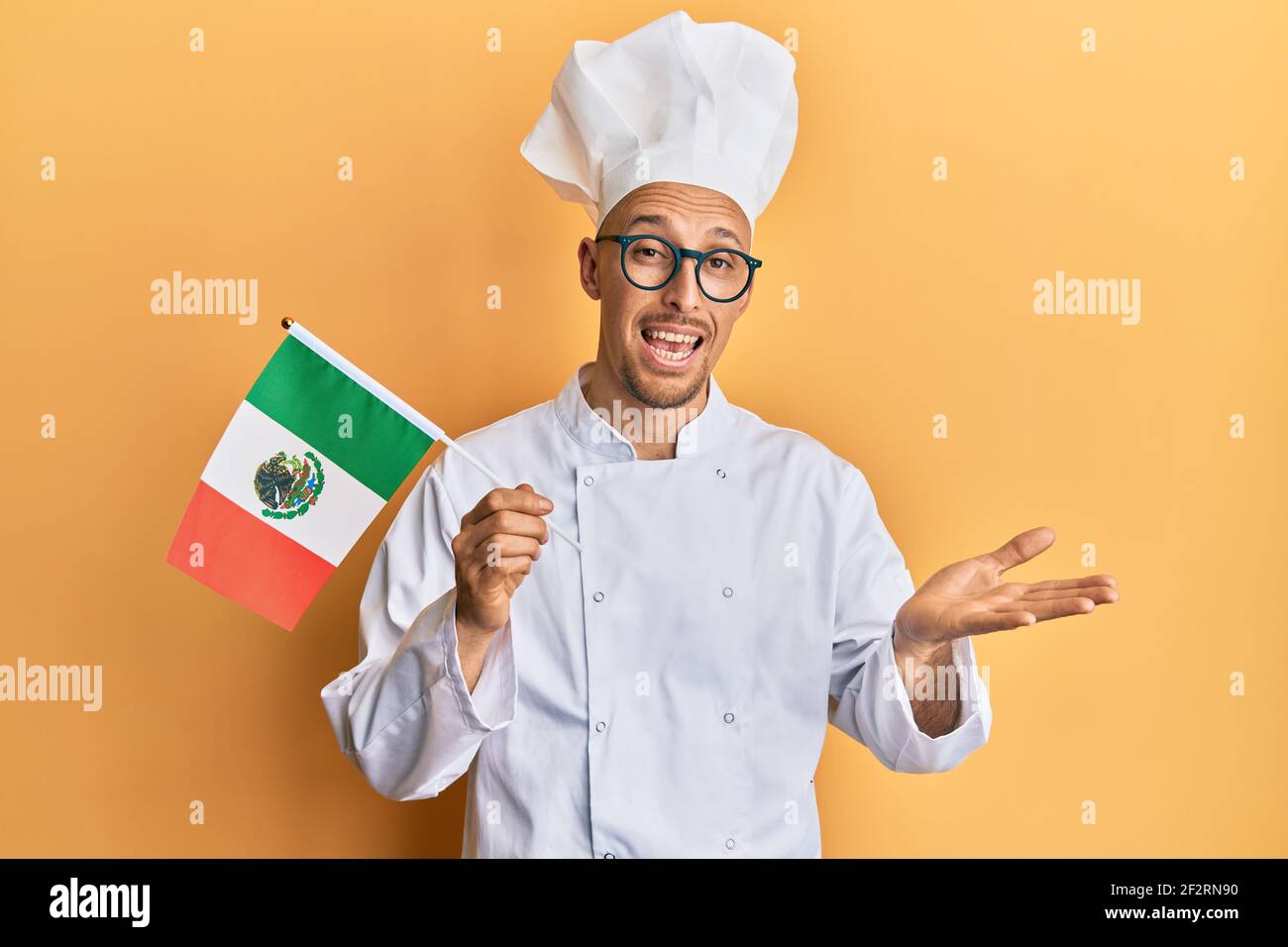 Bald man with beard wearing professional cook apron holding mexico flag ...