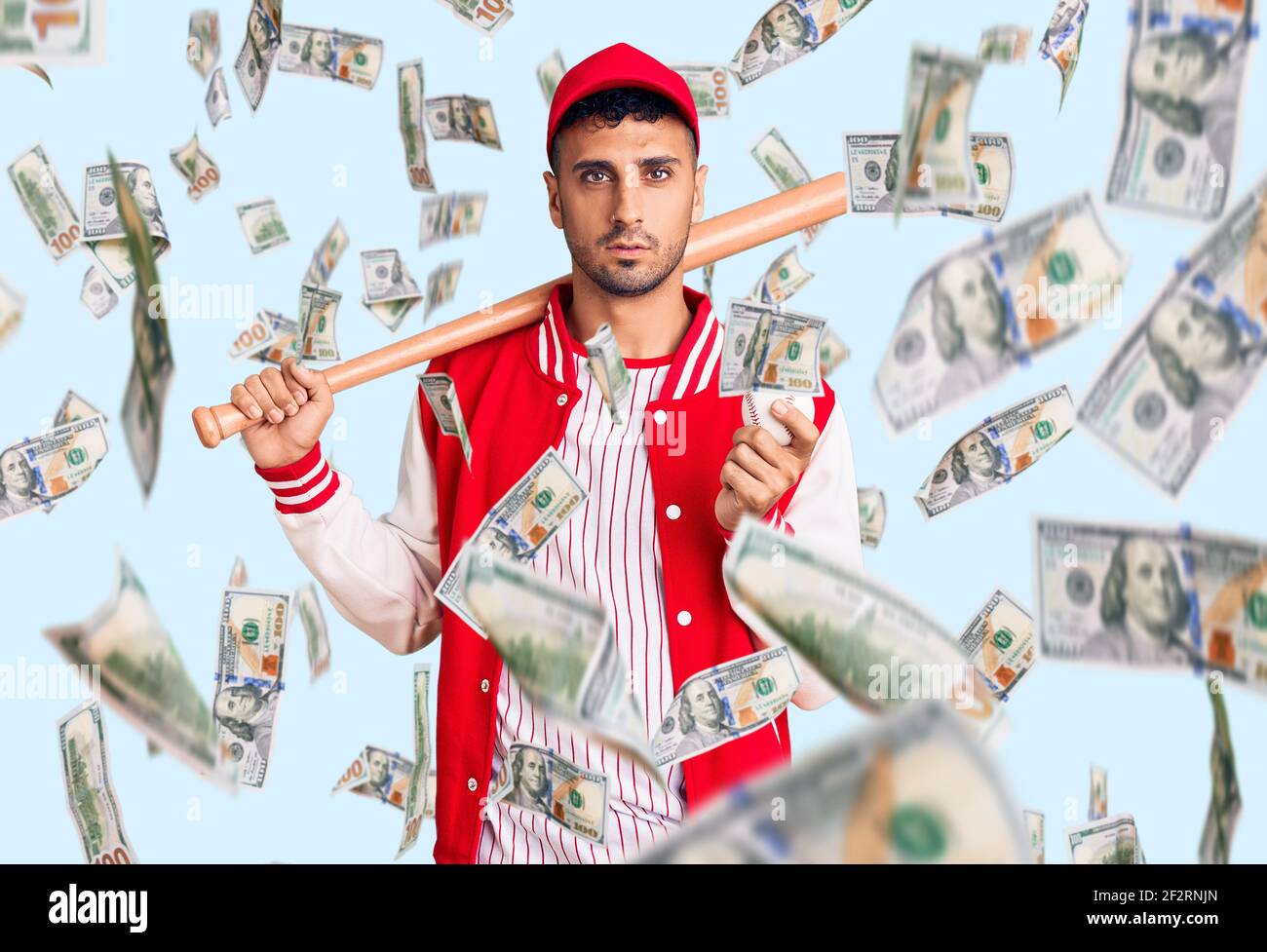 Young hispanic man playing baseball holding bat and ball thinking ...