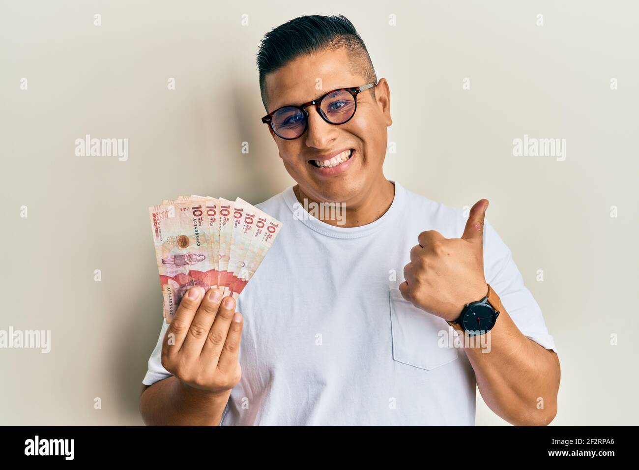Young latin man holding 10 colombian pesos banknotes smiling happy and ...