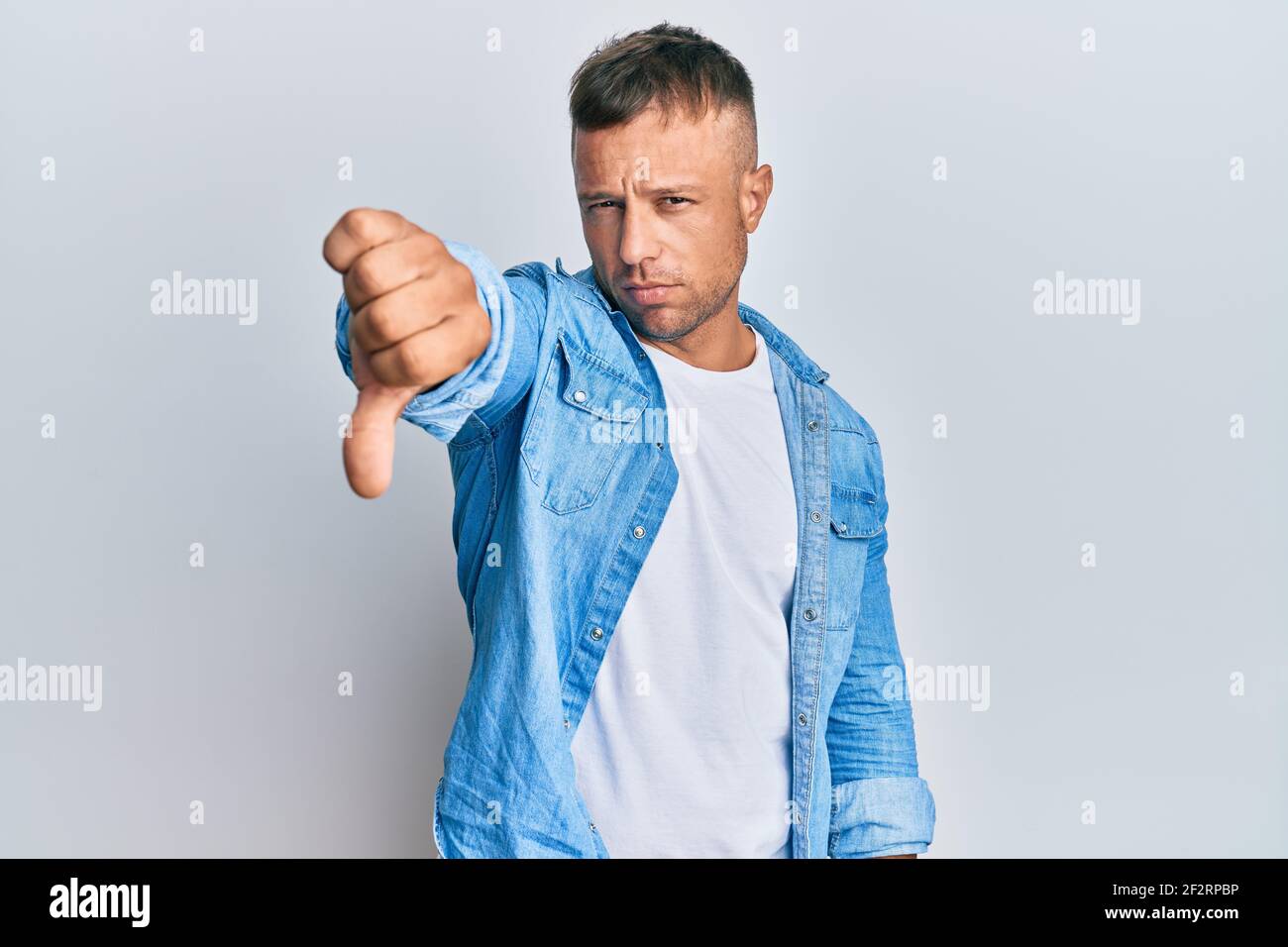 Handsome muscle man wearing casual denim jacket looking unhappy and ...