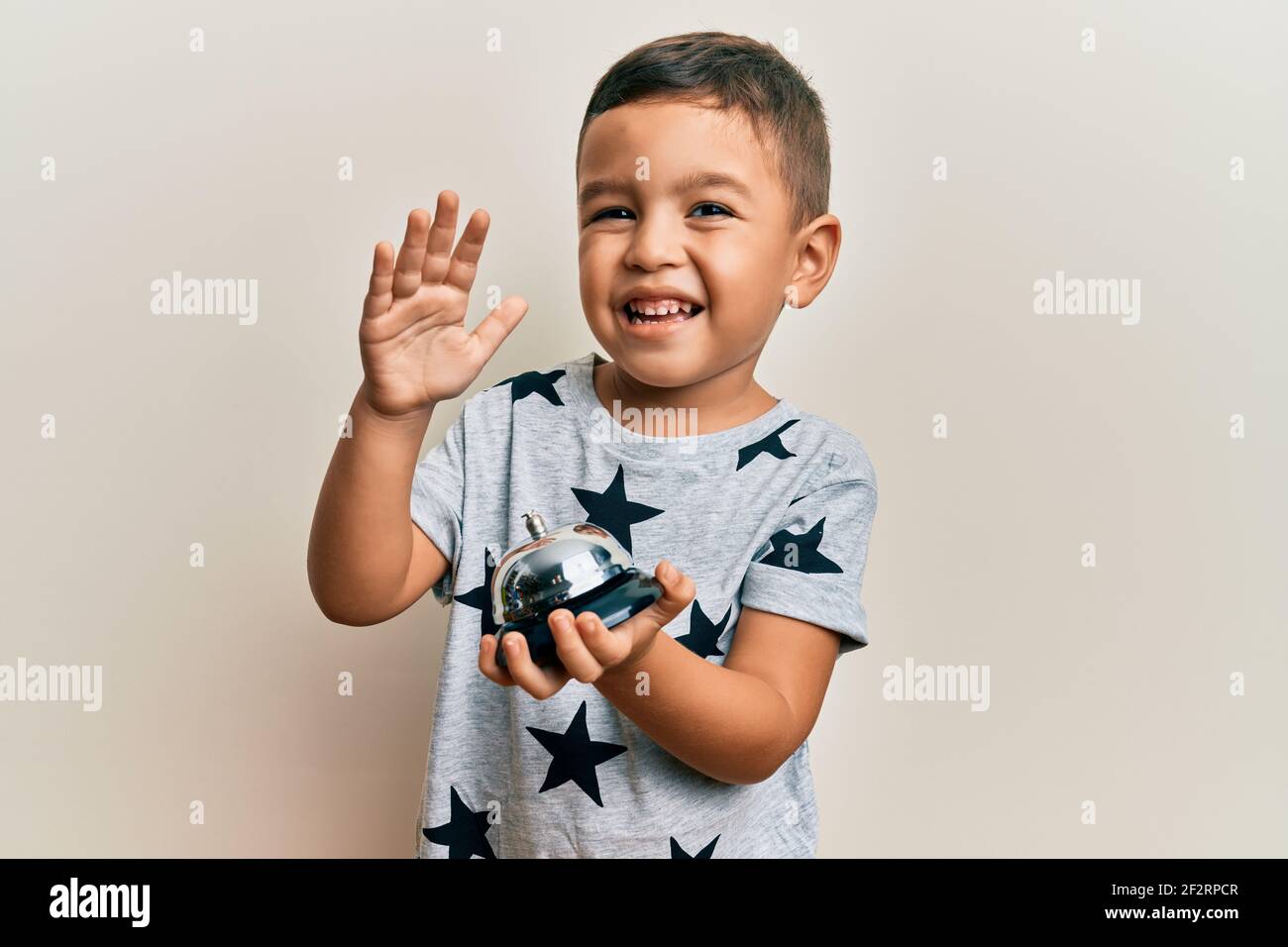 Adorable latin toddler smiling happy using receptionist ring bell over ...