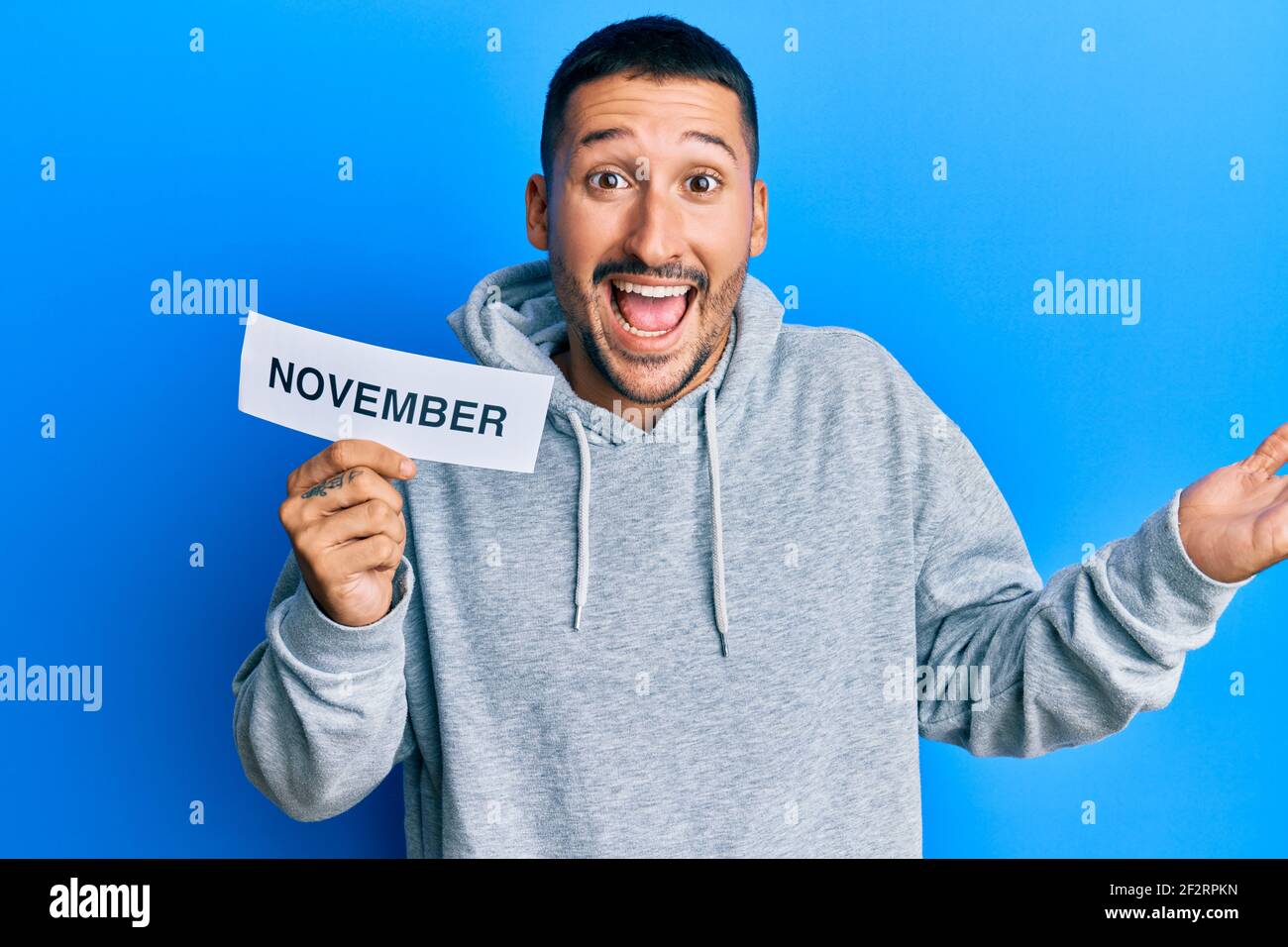 Handsome man with tattoos holding november word on paper celebrating ...