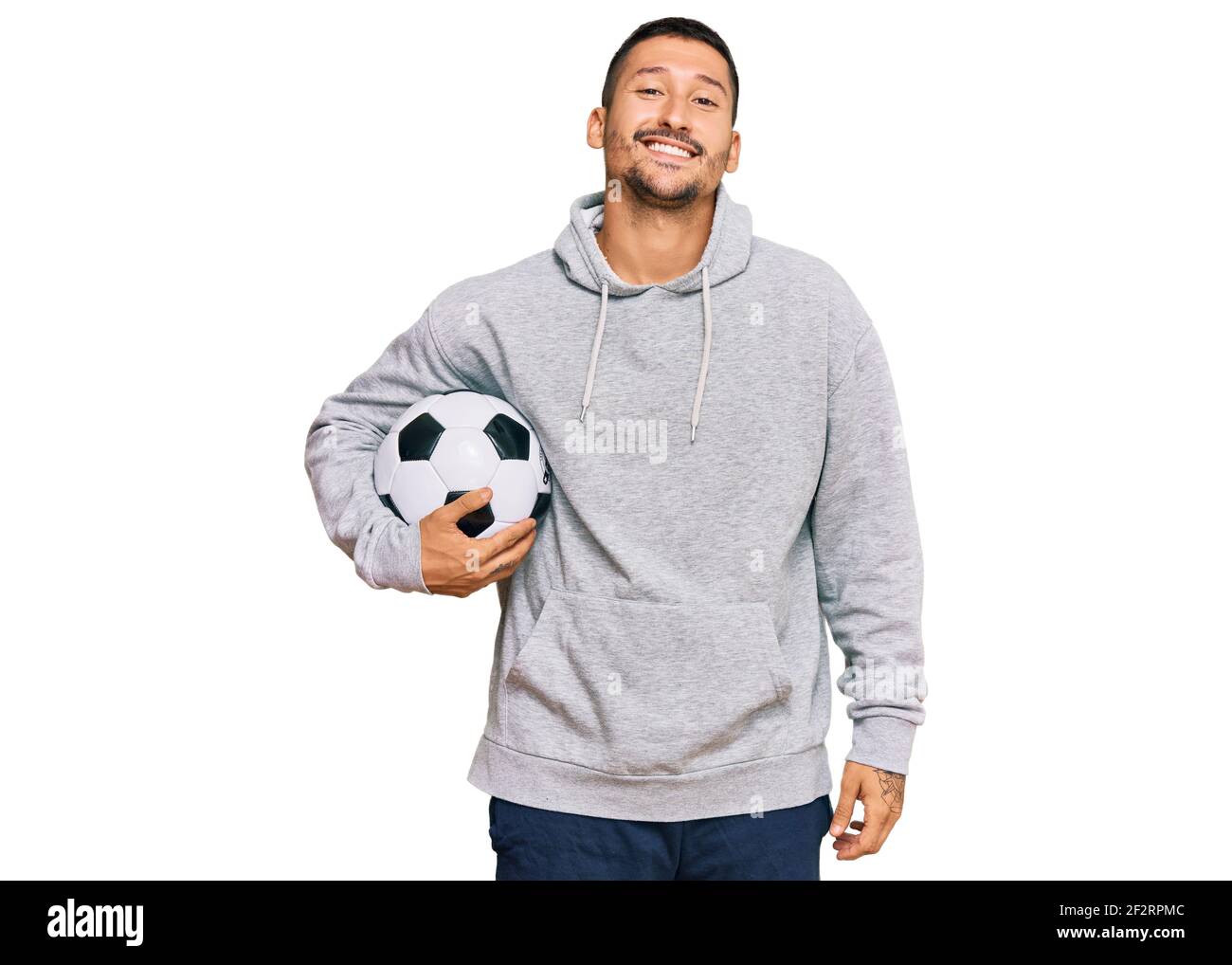 Handsome man with tattoos holding soccer ball looking positive and ...