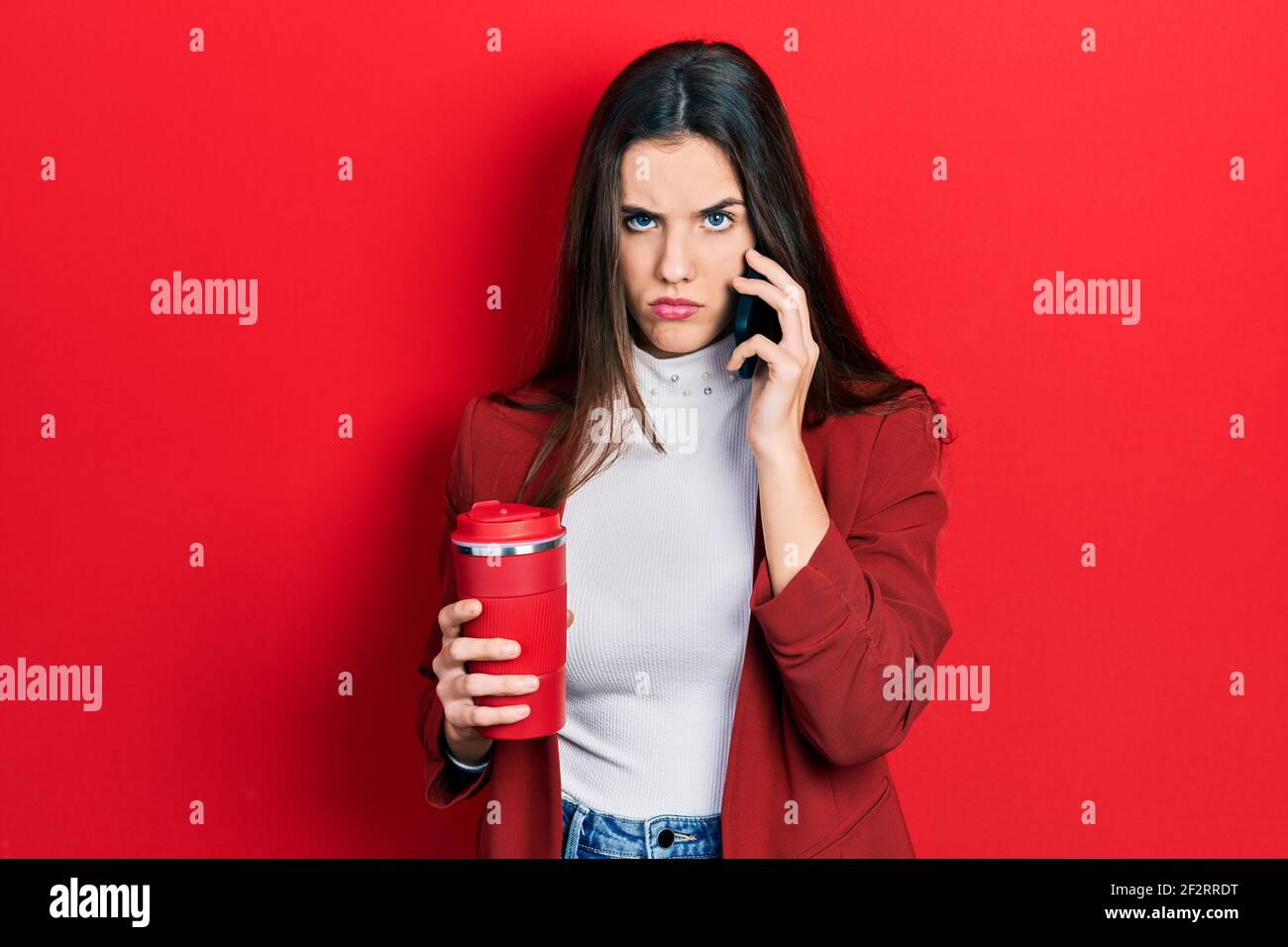 Young brunette teenager talking on smartphone and drinking coffee ...
