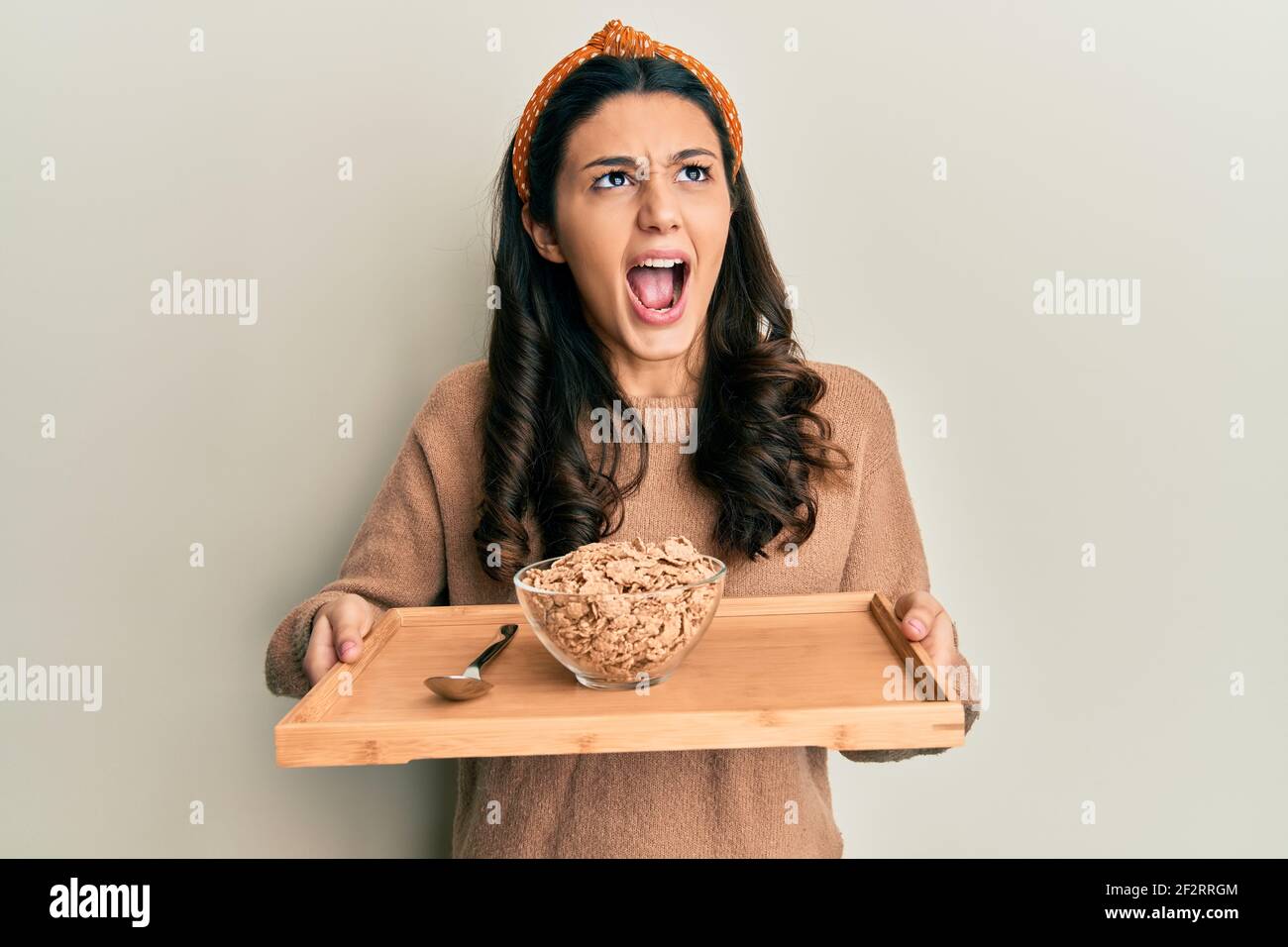 Young hispanic woman holding tray with healthy whole grain cereals ...
