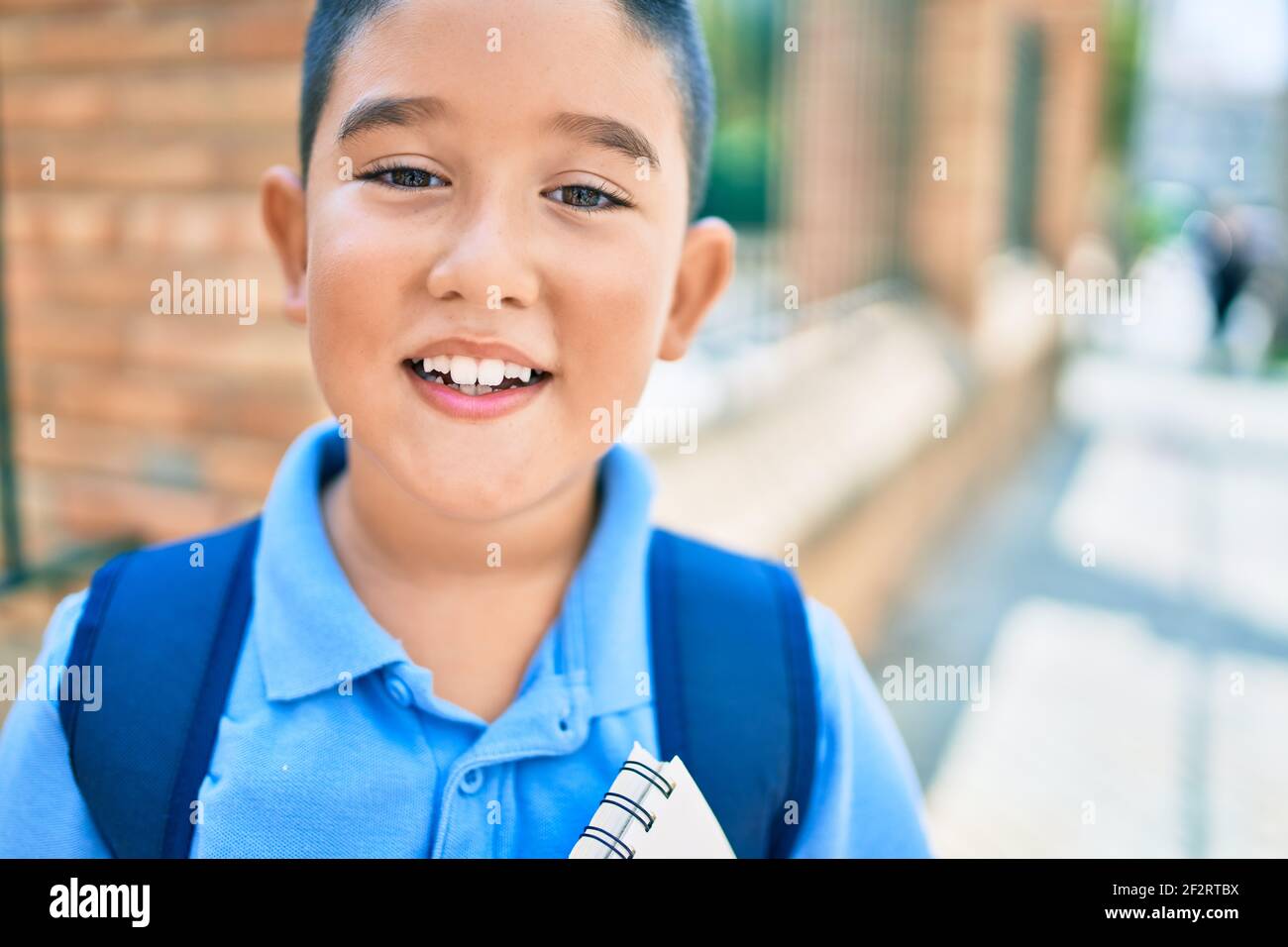 Adorable student boy smiling happy holding book at street of city Stock ...