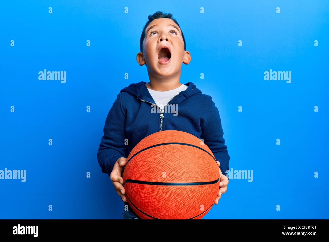Little boy hispanic kid holding basketball ball angry and mad screaming ...