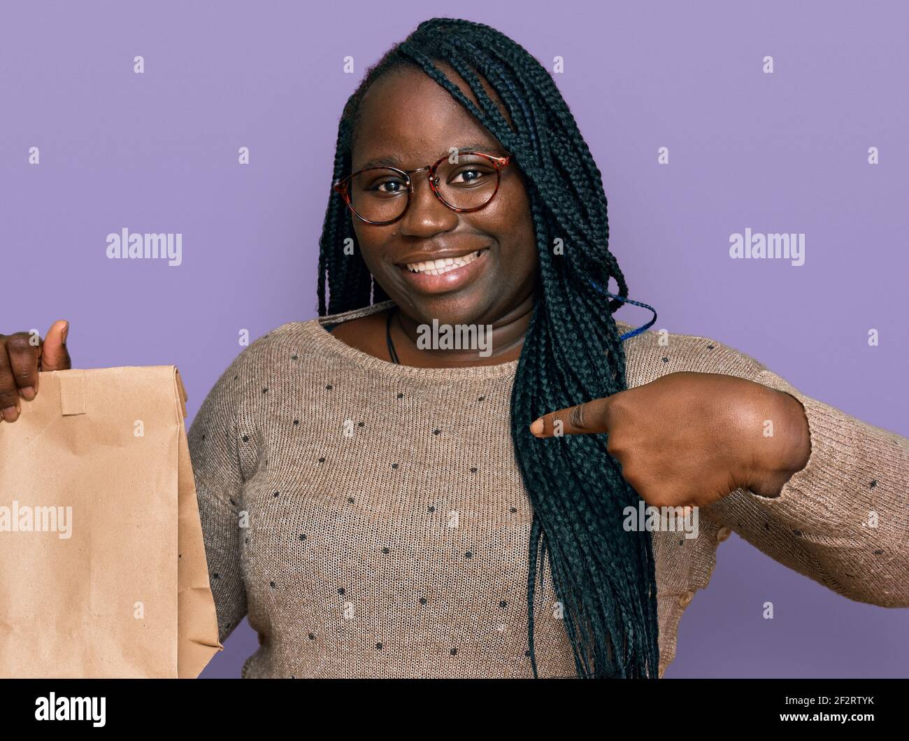 Young black woman with braids holding take away paper bag pointing ...