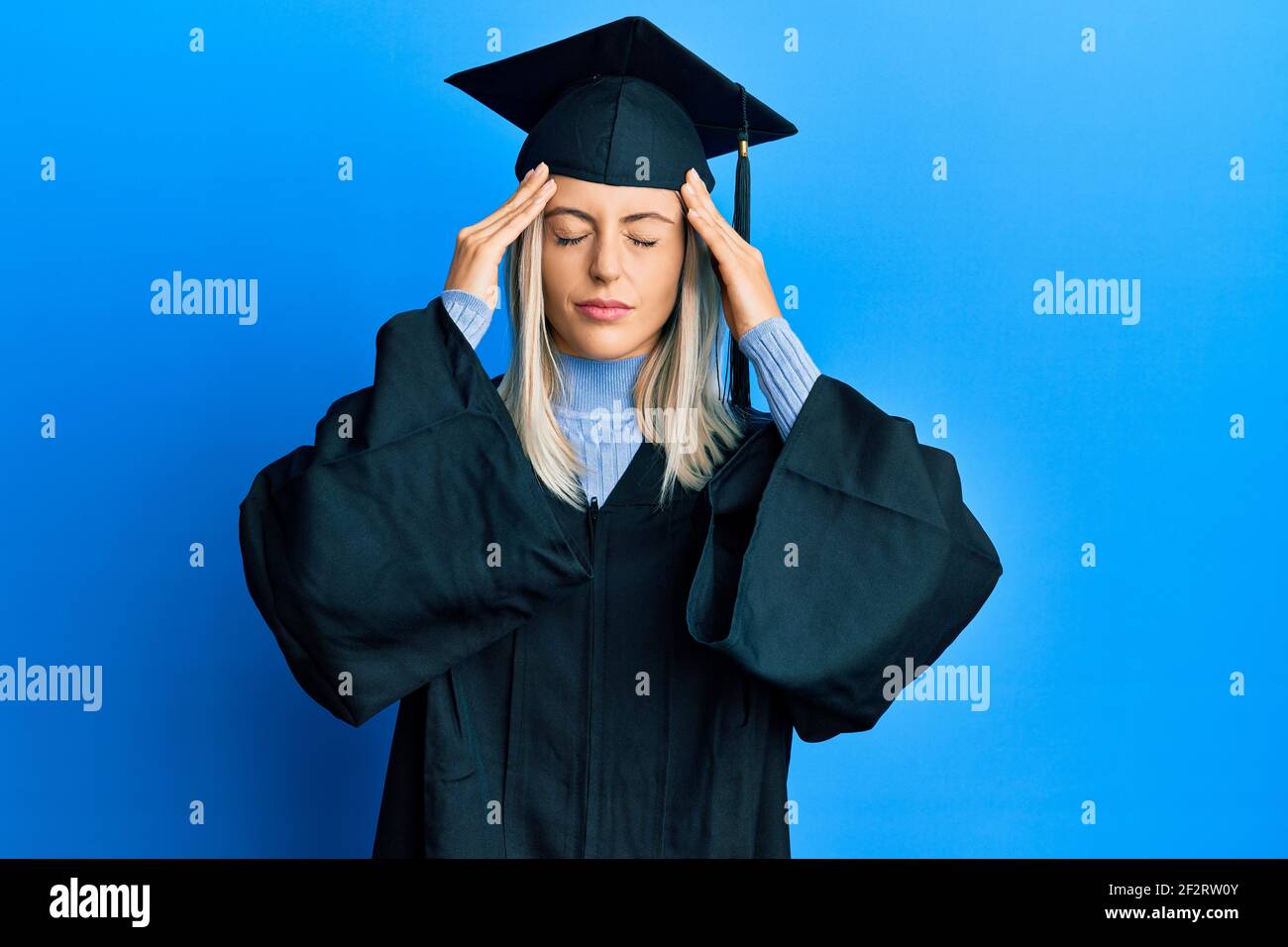 Beautiful blonde woman wearing graduation cap and ceremony robe with ...
