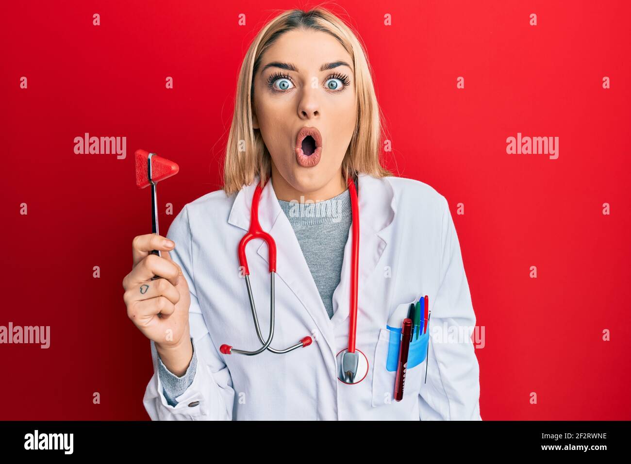 Young caucasian woman wearing doctor uniform holding medical reflex ...