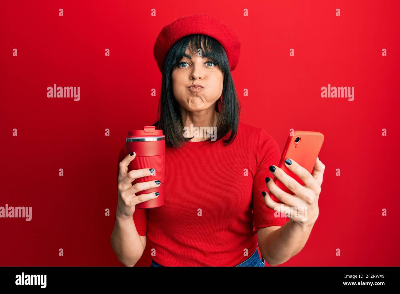 Young hispanic woman using smartphone and drinking a cup of coffee ...
