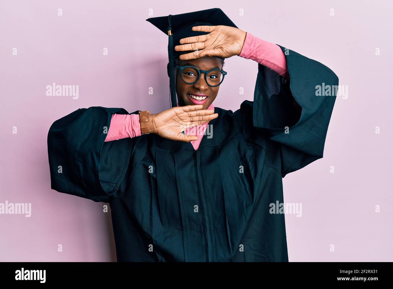 Young african american girl wearing graduation cap and ceremony robe ...