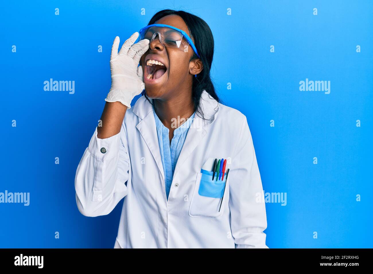 Young african american woman wearing scientist uniform shouting and ...