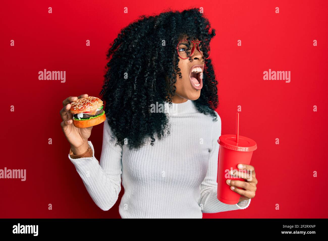 African american woman with afro hair eating a tasty classic burger and ...
