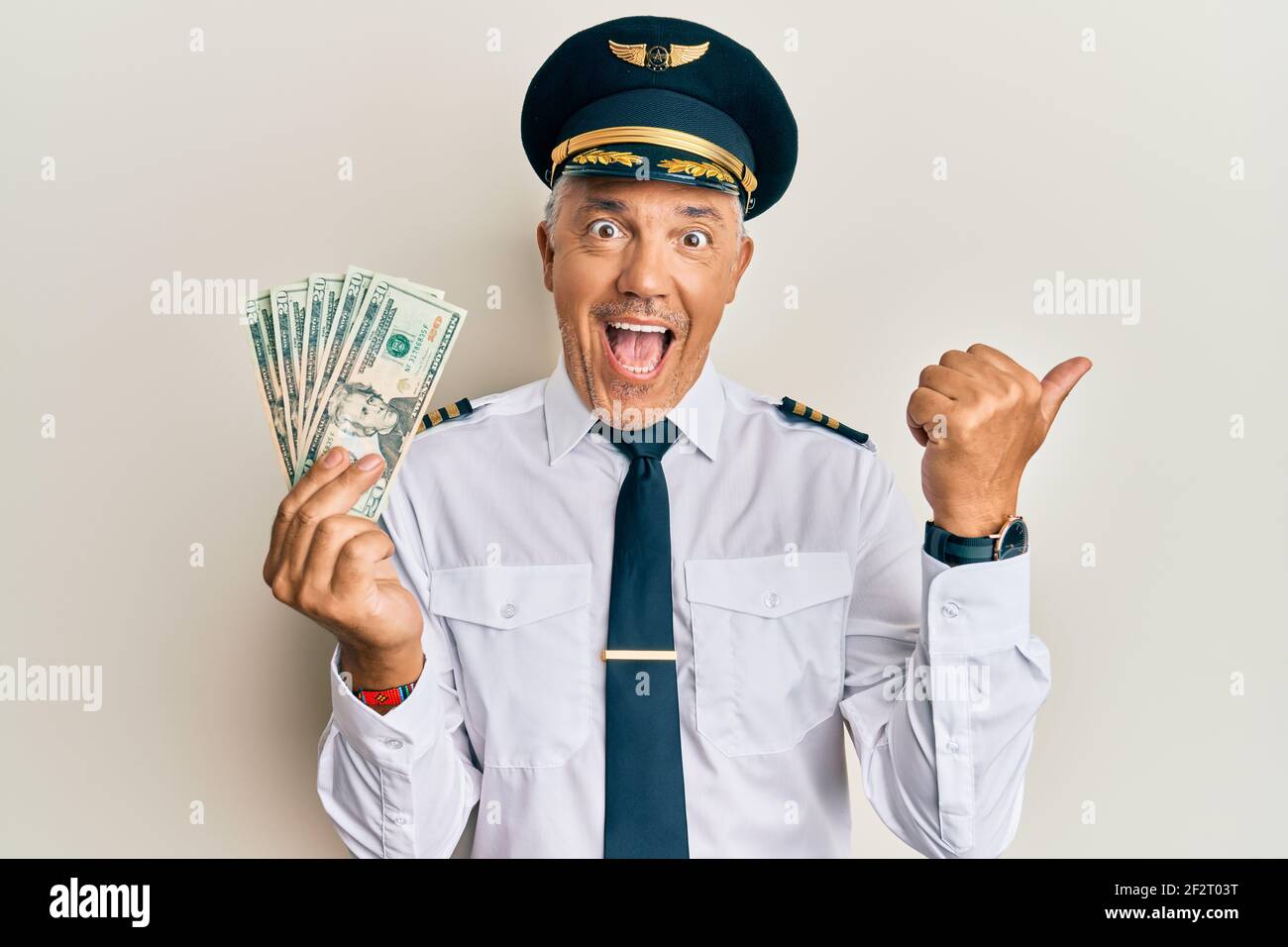 Handsome middle age mature man wearing airplane pilot uniform holding ...