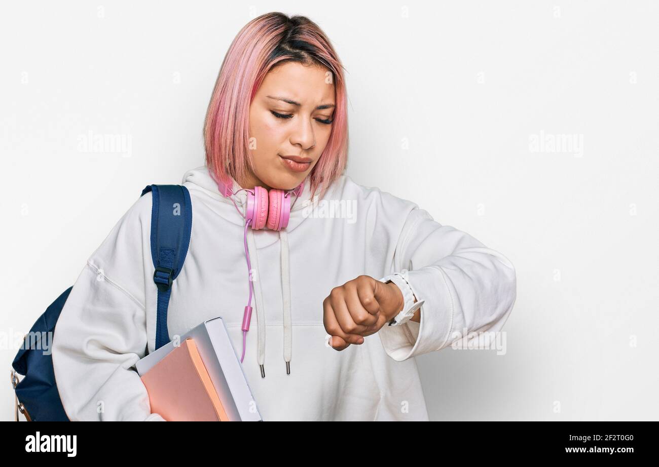 Hispanic woman with pink hair wearing student backpack and headphones ...