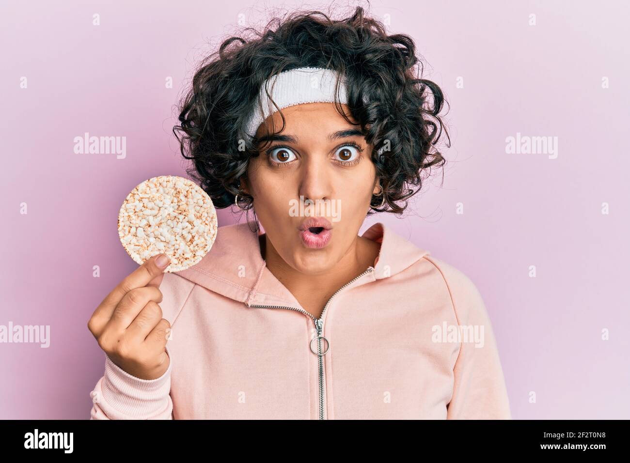 Young hispanic woman with curly hair eating healthy rice crackers ...