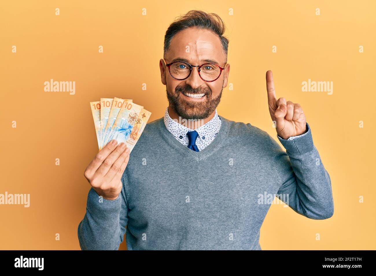 Handsome middle age man holding swiss franc banknotes smiling with an ...