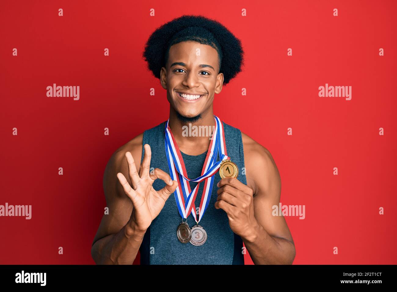 African american man with afro hair wearing winner medals doing ok sign ...