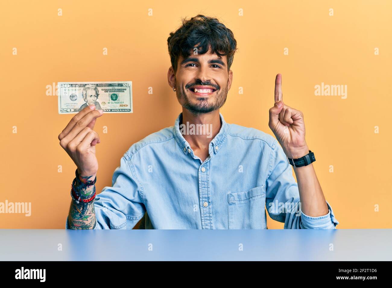 Young hispanic man holding 20 dollar banknote smiling with an idea or ...