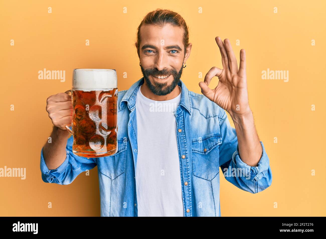 Attractive man with long hair and beard drinking a pint of beer doing ...