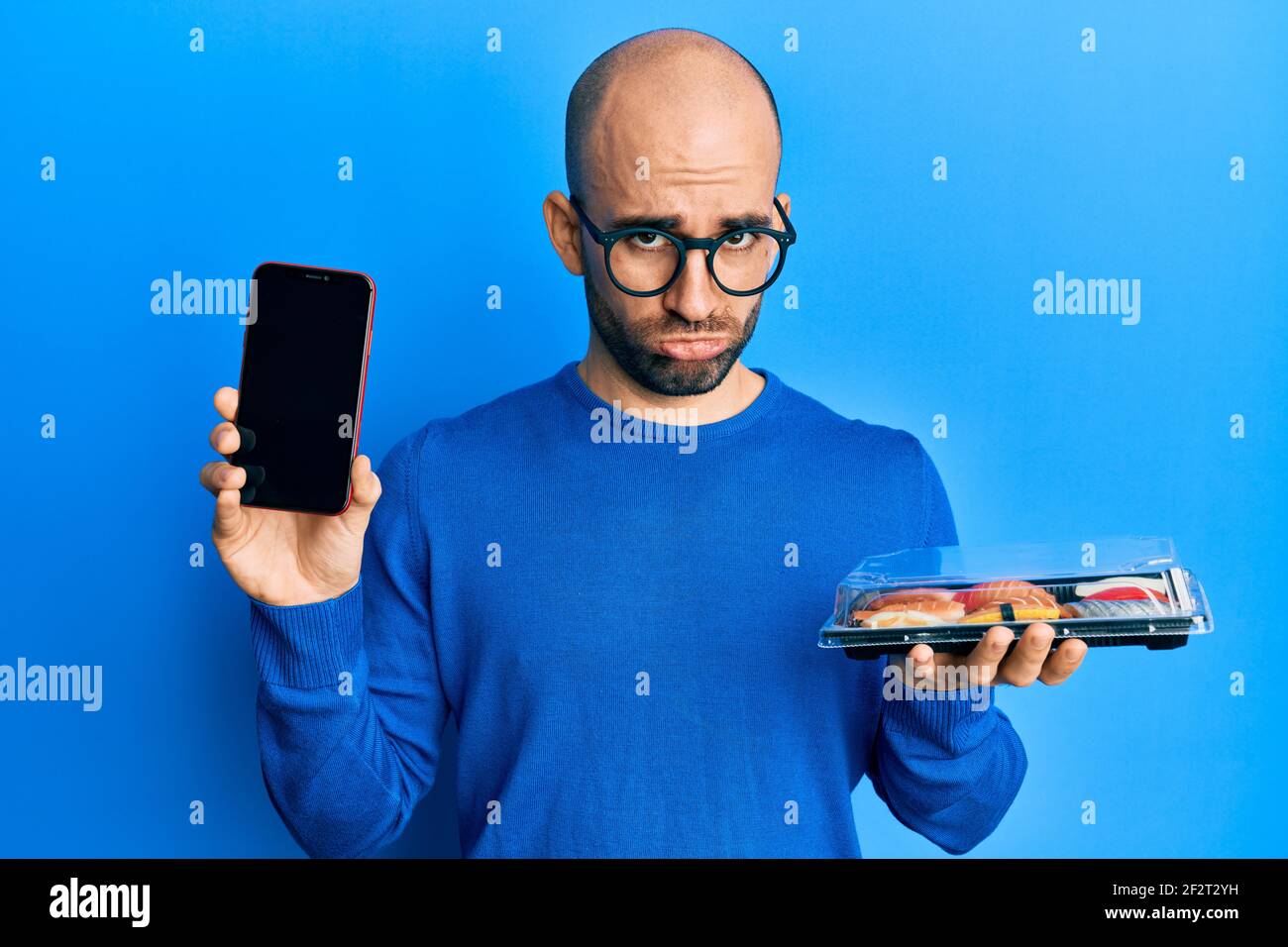 Young hispanic man holding take away food showing smartphone screen ...