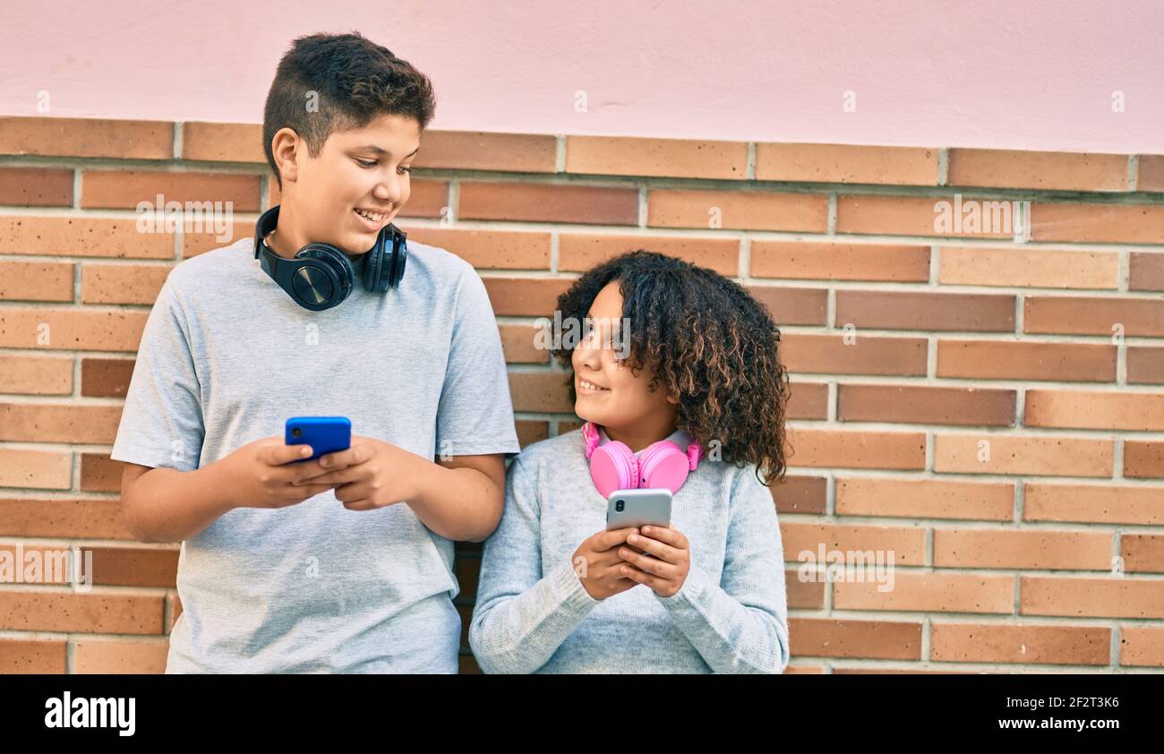 Adorable latin brother and sister smiling happy using smartphone at the ...