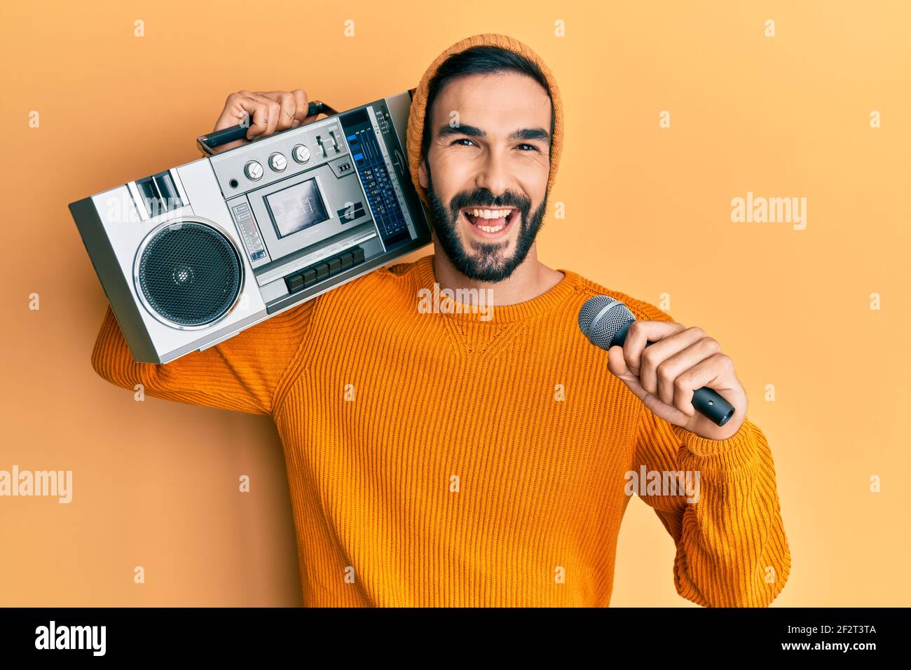 Young hispanic man holding boombox, listening to music singing with ...