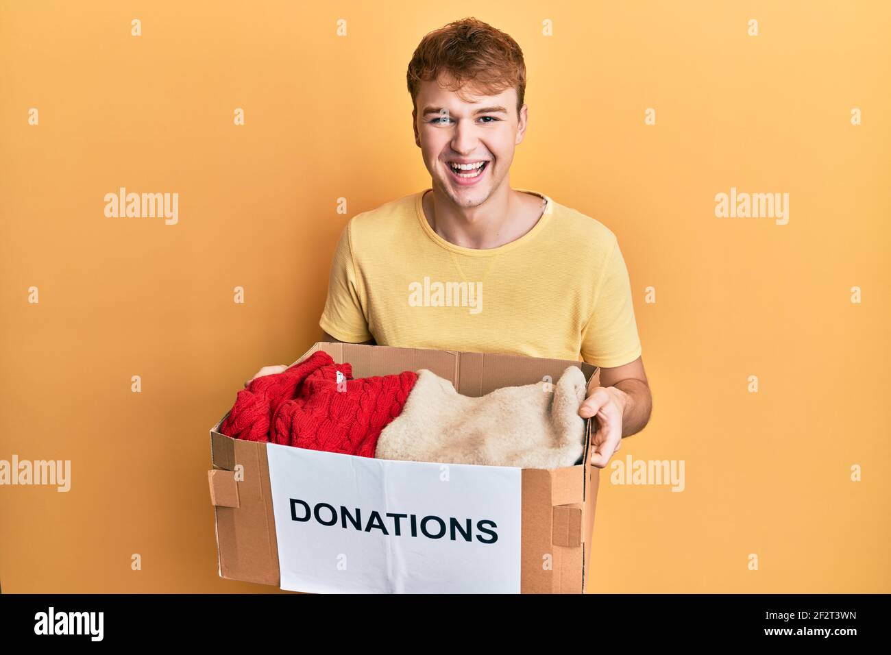 Young caucasian man holding donations box for charity smiling and ...