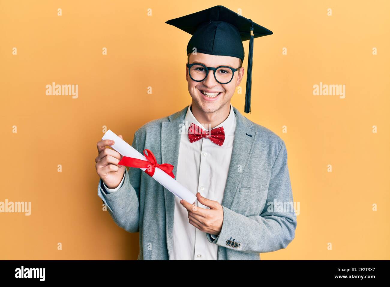 Young caucasian nerd man wearing glasses and graduation cap and holding ...