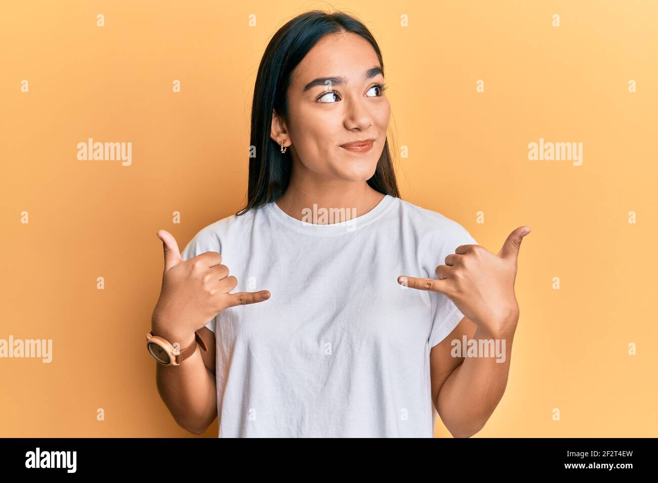 Young asian woman doing shaka sign with hands smiling looking to the ...