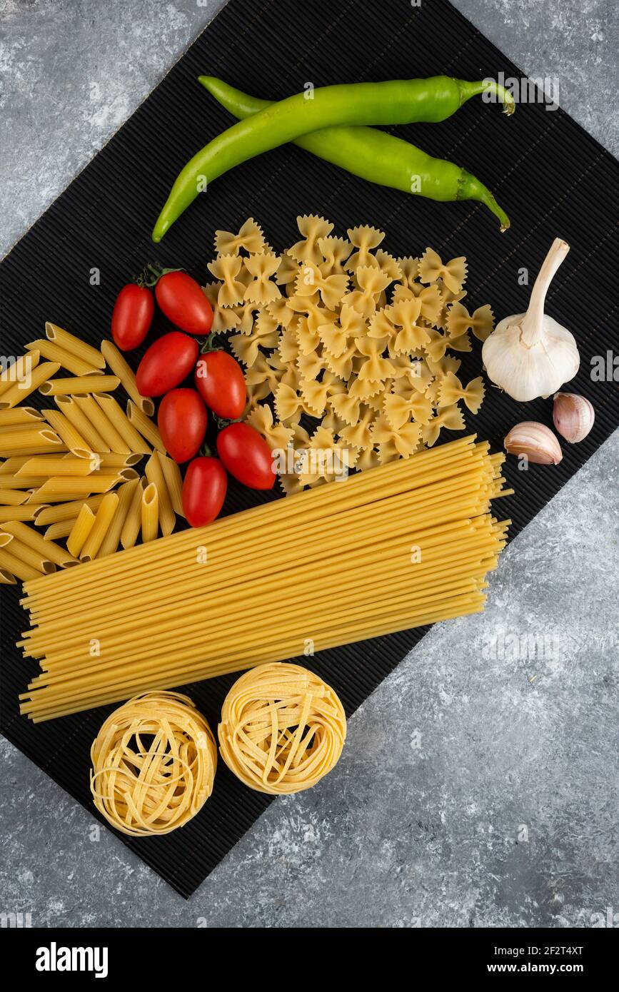 Various raw pasta and vegetables on black bamboo sheet Stock Photo - Alamy