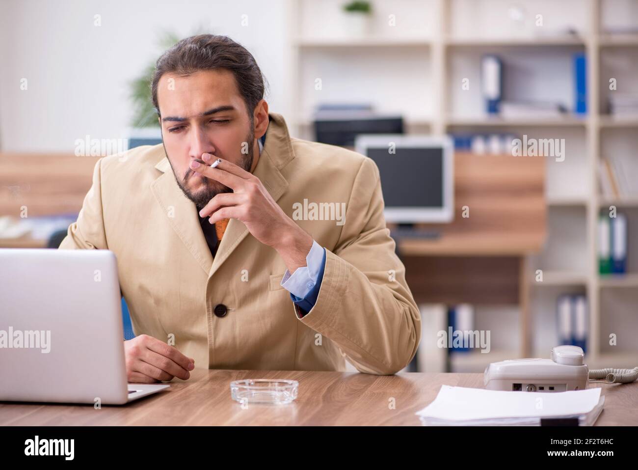 Sick cigarette addicted male employee working in the office Stock Photo ...
