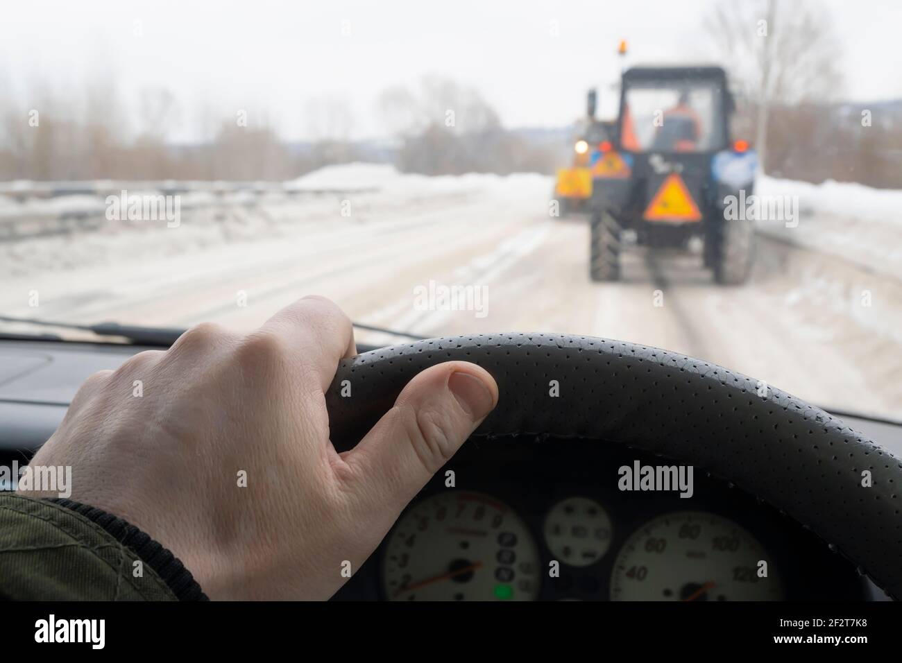 the driver's hand behind the wheel of a car that drives behind two slow ...