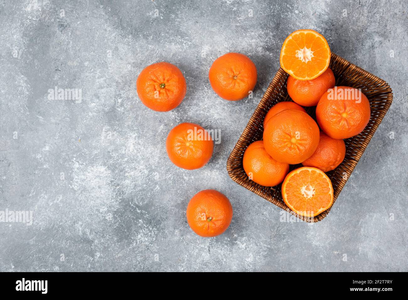 A wicker box full of juicy orange fruits on stone background Stock ...