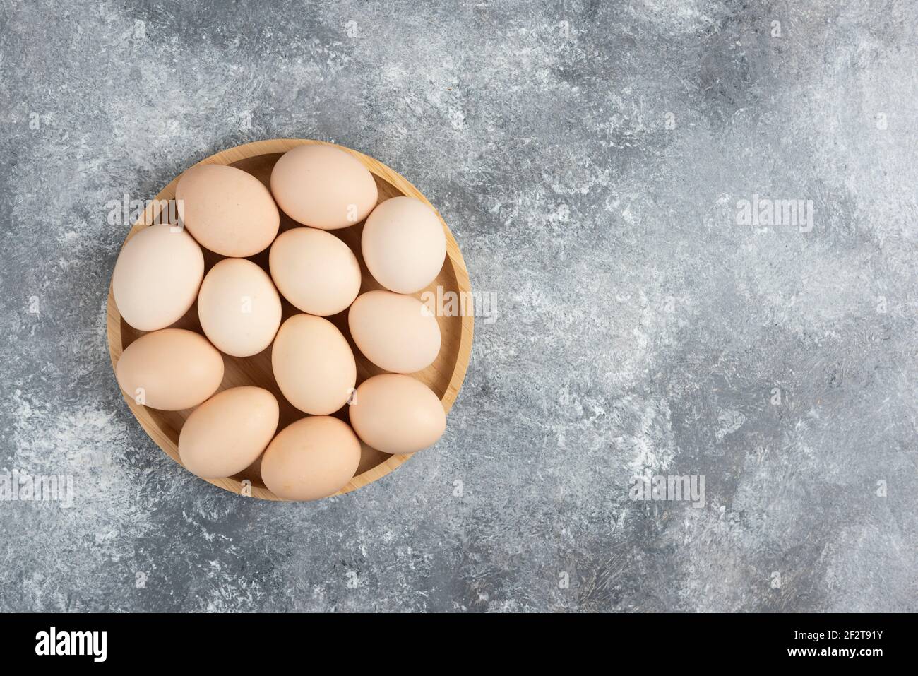 Wooden plate of fresh organic raw eggs on marble surface Stock Photo ...