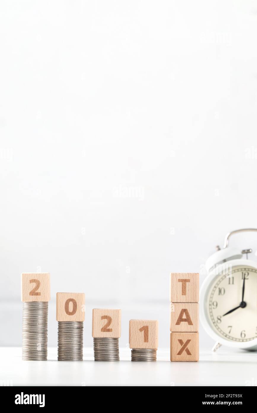 Concept of tax season approaching with wooden blocks, coins and alarm ...