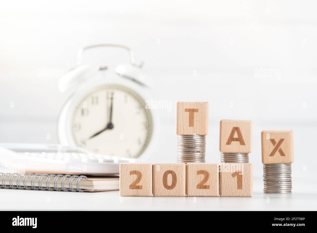 Concept of tax season approaching with wooden blocks, coins and alarm ...