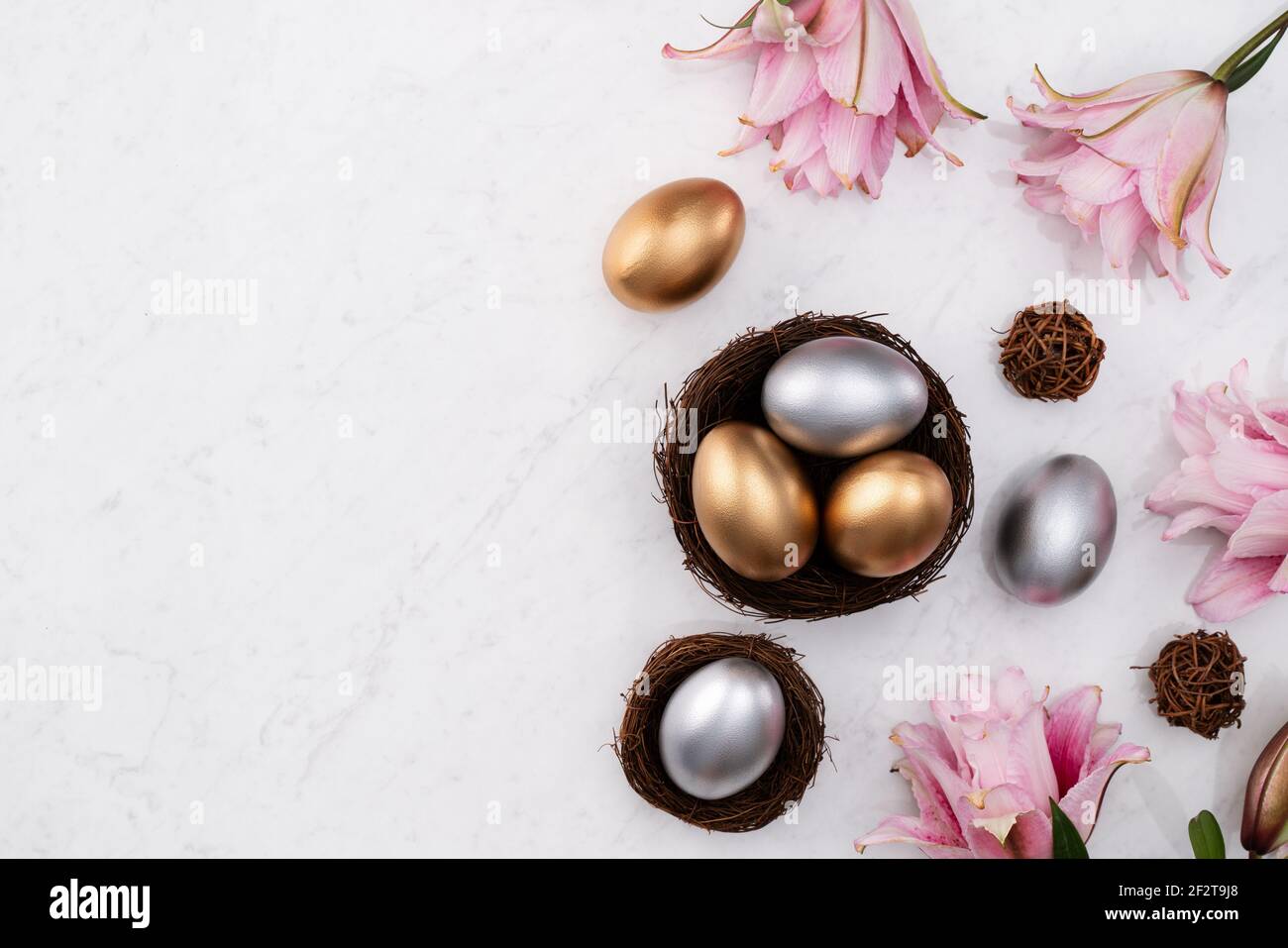Golden and silver Easter eggs in the nest with pink lily flower on ...