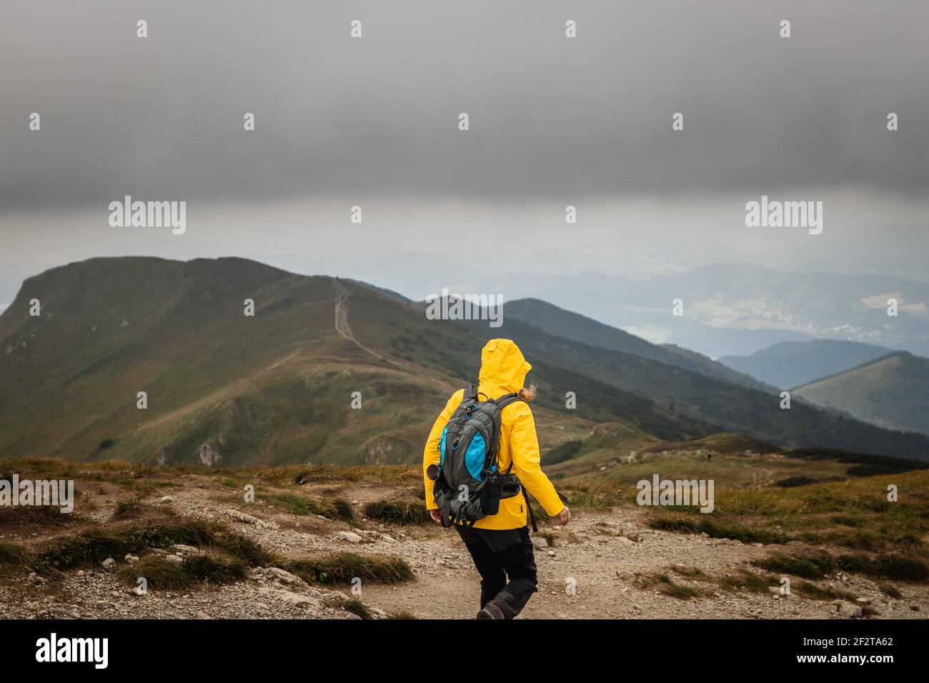 Hiking at mountains in bad weather. Woman with backpack walking at ...