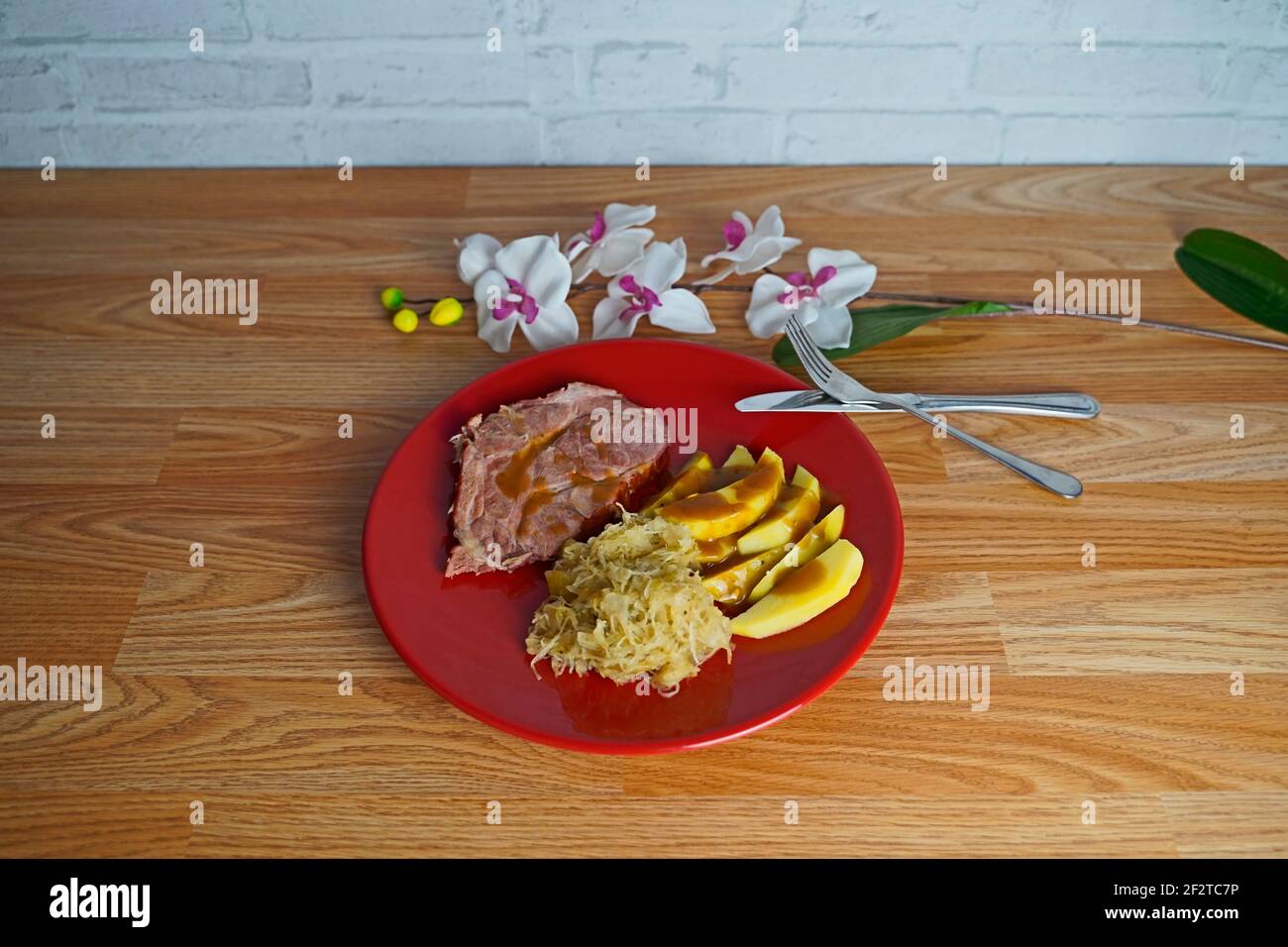 salted meat with sauerkraut and potato wedges arranged on red plate Stock Photo - Alamy