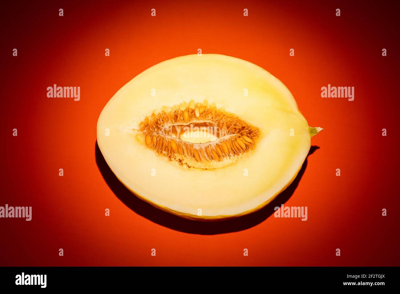 Half yellow melon on dark red background. Top view, dramatic light ...