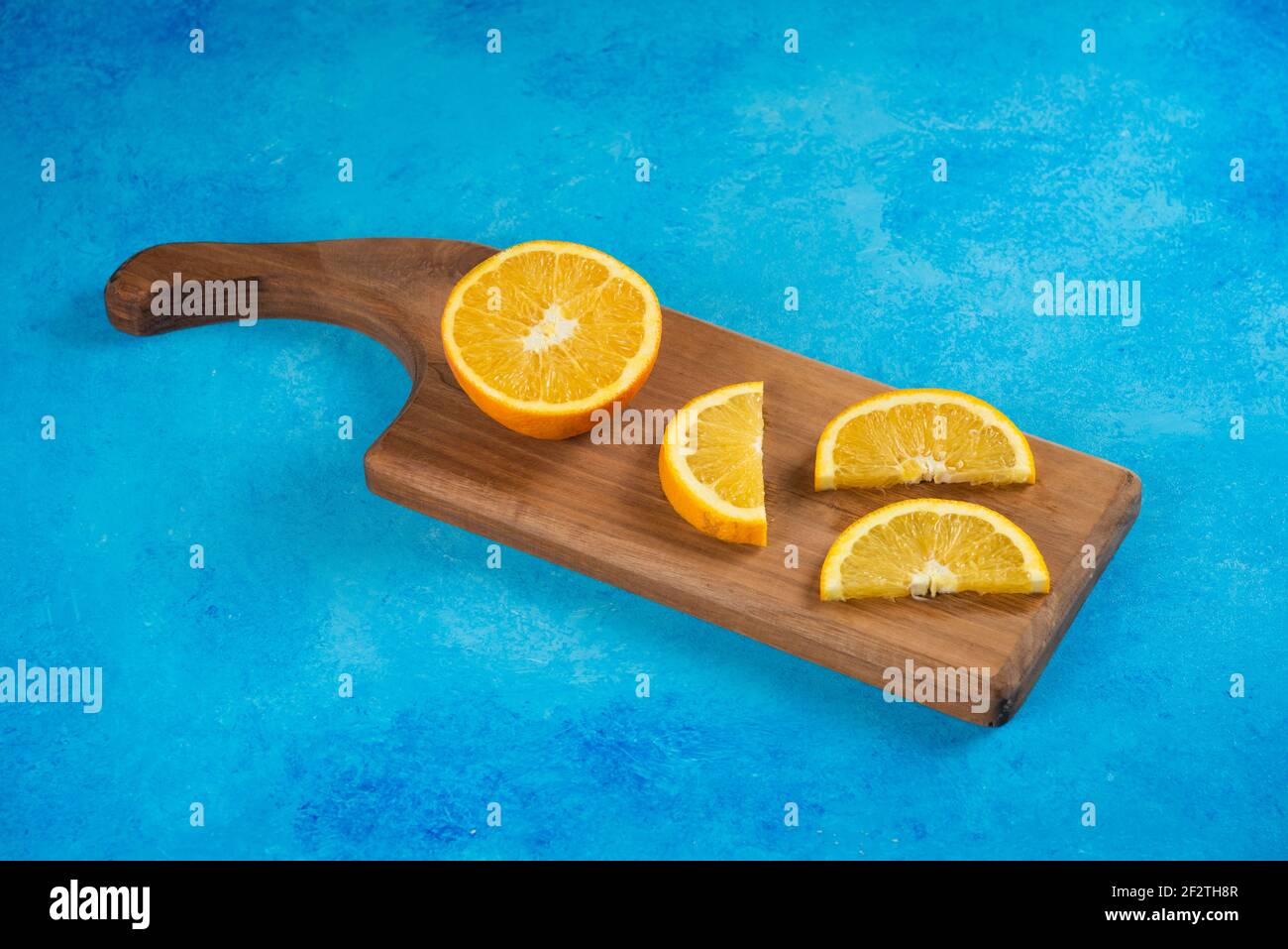 Sliced orange on a wooden board on a blue background Stock Photo - Alamy