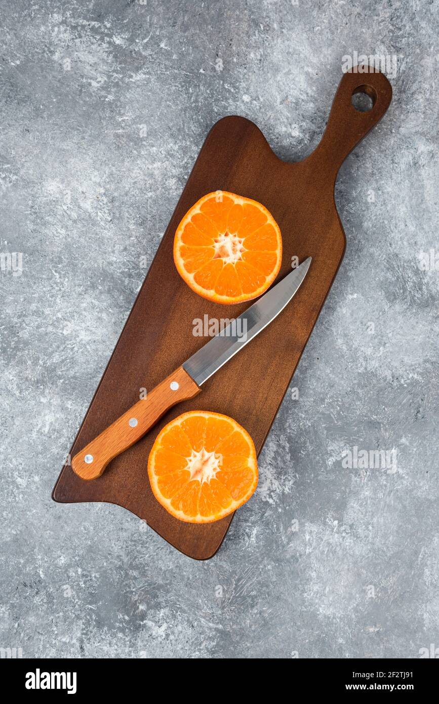 a wooden board of juicy slices of orange fruit with a knife on stone ...